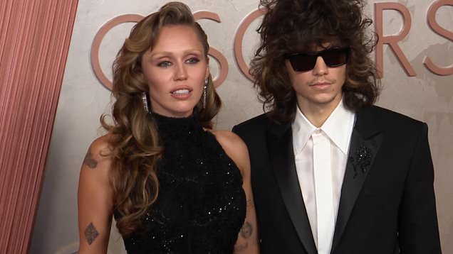 Miley Cyrus strikes a pose in black halter gown and gloves at Oscars