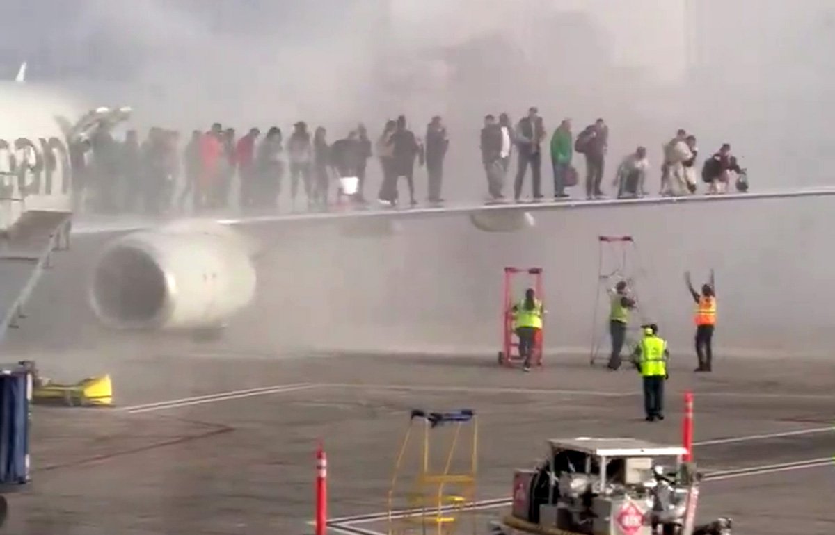 Passengers evacuate onto plane's wing after engine bursts into flames