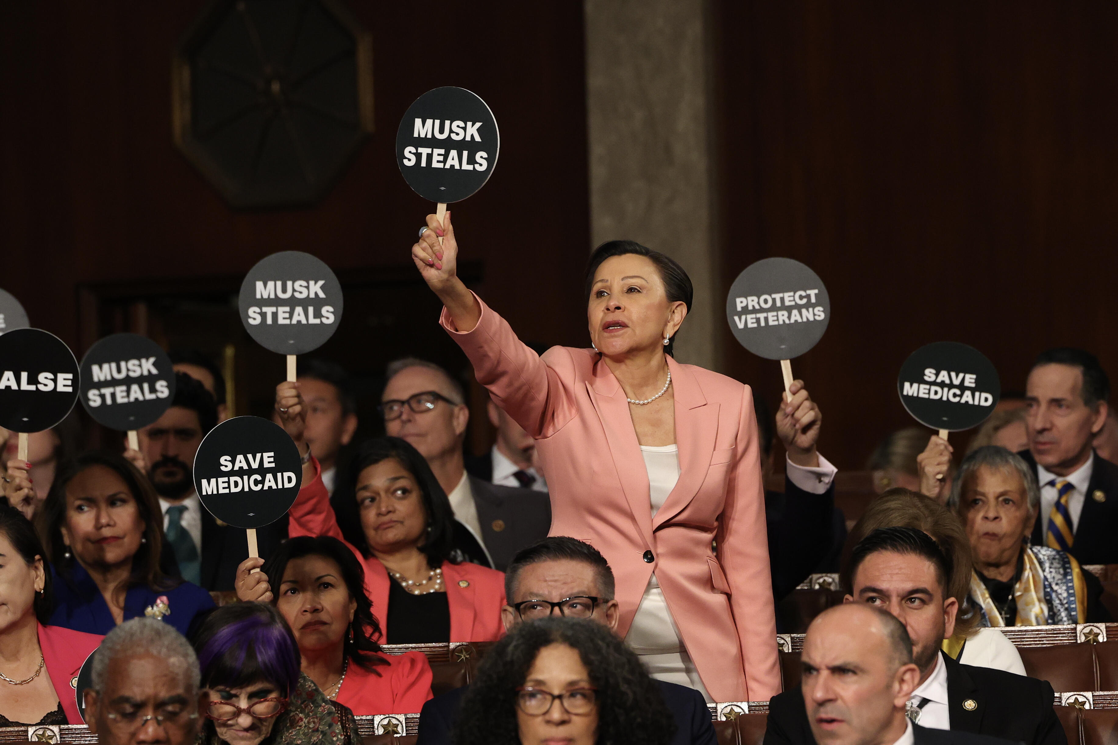 Progressive Lawmakers Hold Up Protest Signs During President Trump's Speech