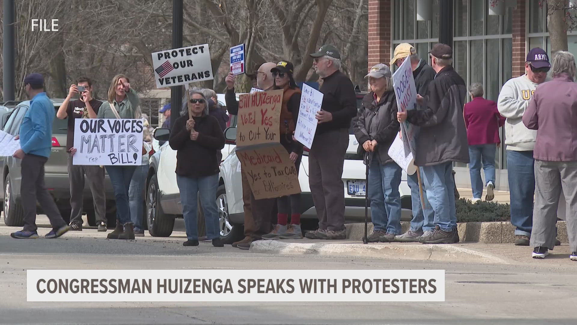 U.S. Congressman Bill Huizenga speaks with demonstrators outside his office