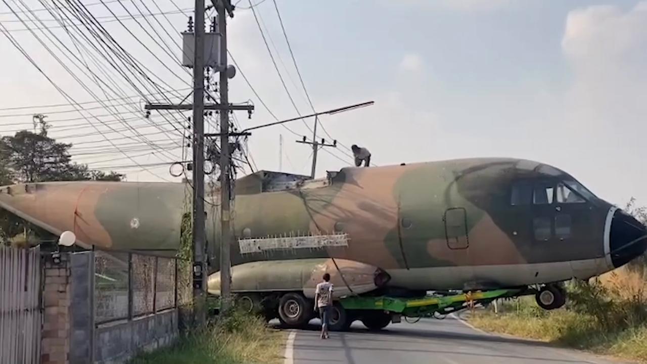Truck carrying military plane navigates a tight corner