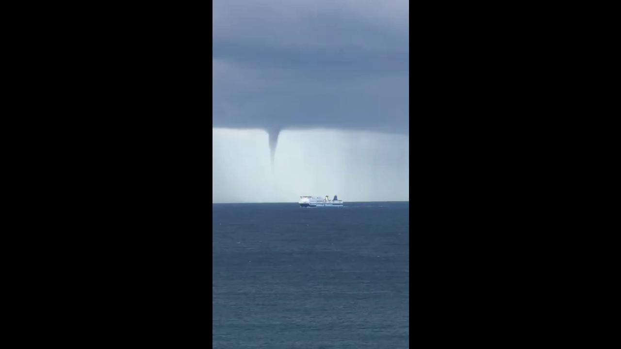 Waterspout tornado swirls past cruise ship in Bay of Palma