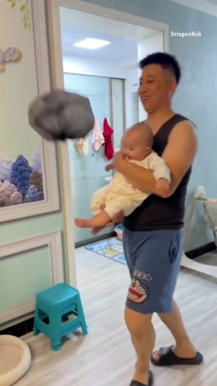 Dad Laughs With Baby Playing a Balloon-Kick Game With a Trash Bag