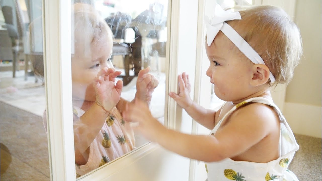 The twin baby girls laugh adorably through the glass