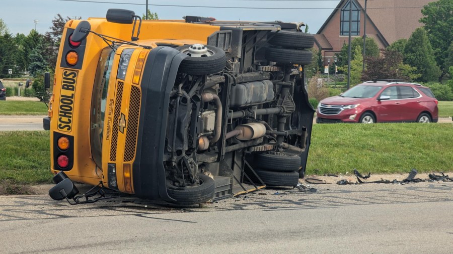 Staffer, other driver injured after crash causes school bus to roll