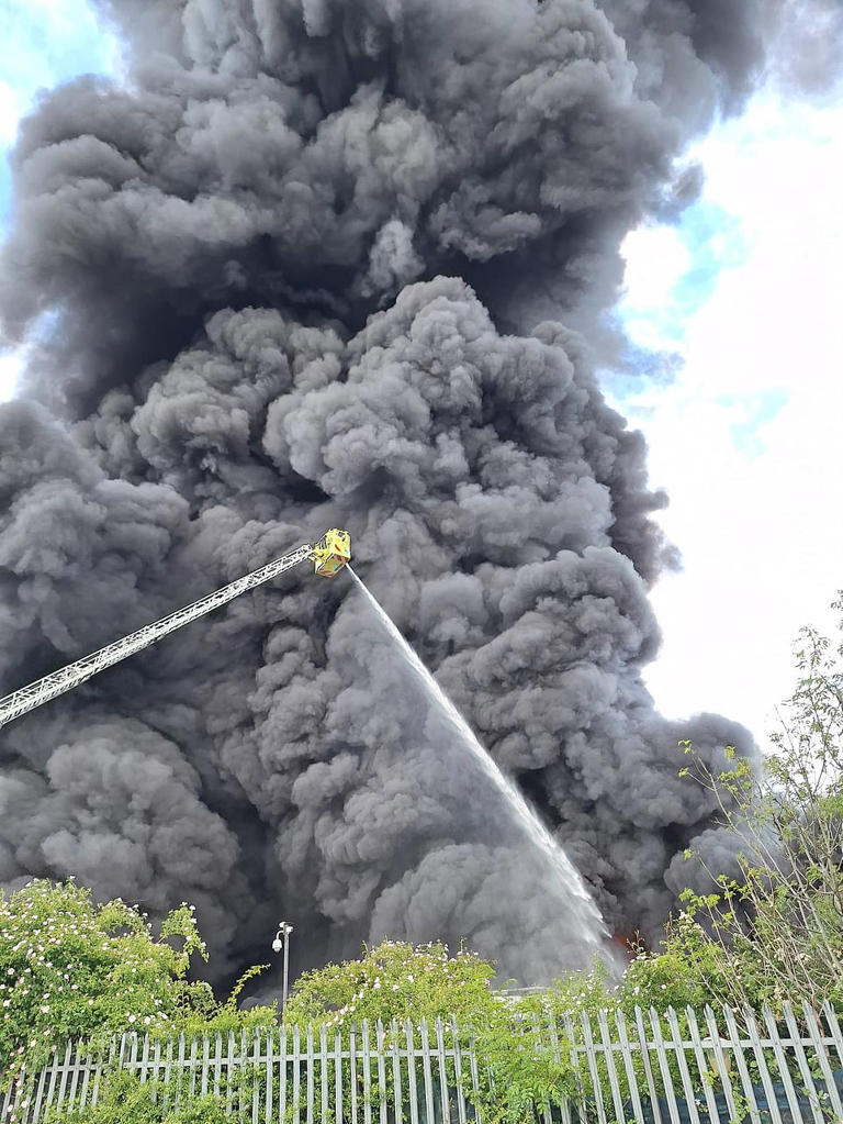 Firefighters rush to massive warehouse blaze as enormous plume of smoke is seen 10 miles away