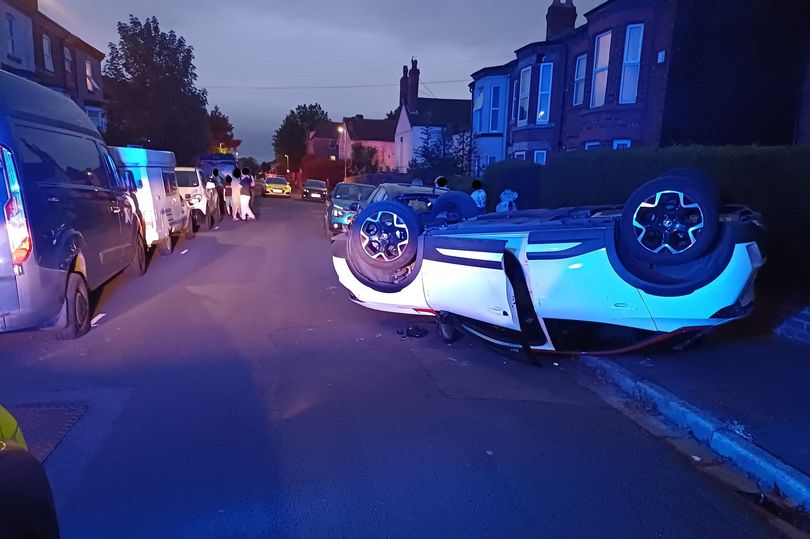 Car upside down in street after collision with parked vehicle