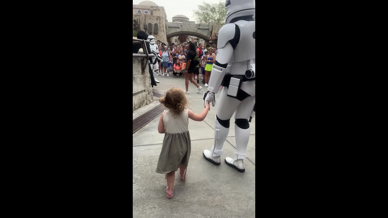 Young girl holds hands with stormtrooper in magical Disney moment