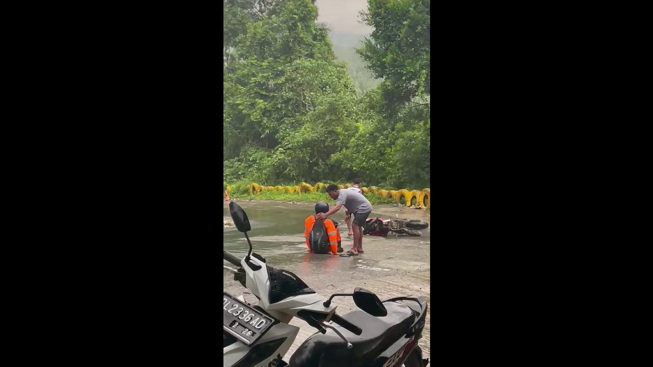 Motorcycle rider takes a tumble on wet road