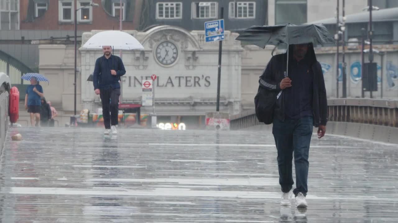 Members of the public attempt to shelter during heavy rain in London ...