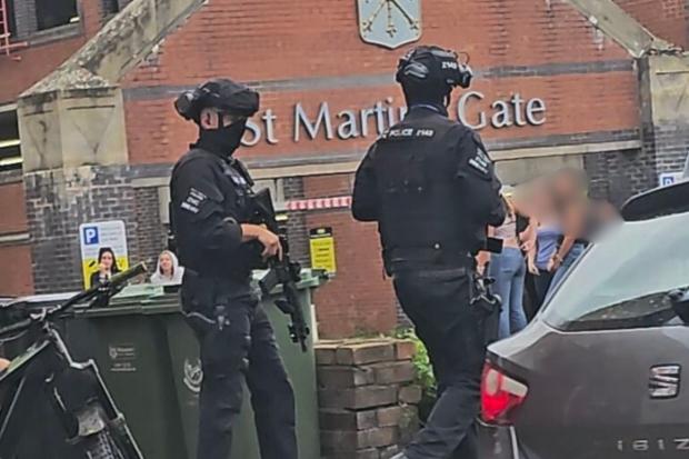 Armed officers outside city car park after police helicopter circles ...