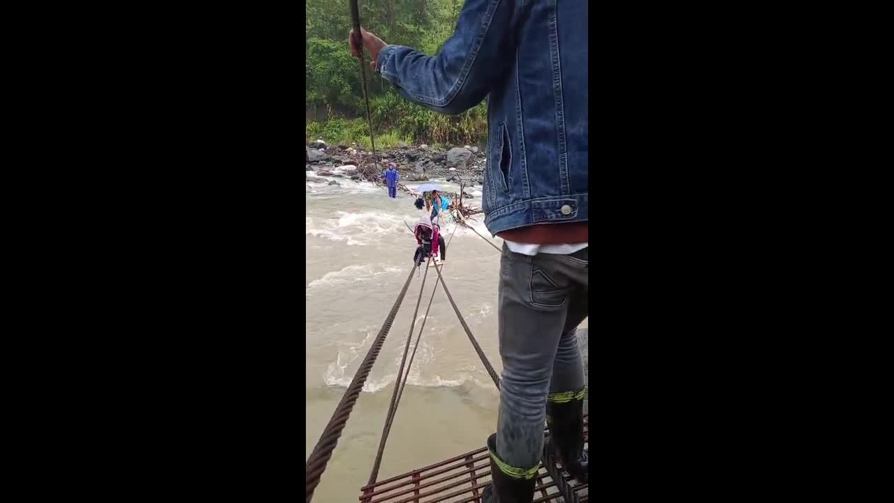 Locals crawl across broken bridge as floods batter the Philippines