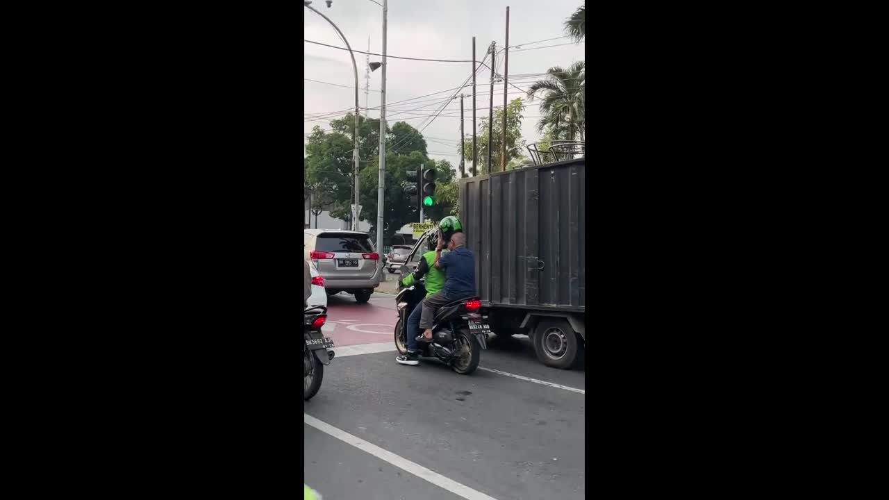 Elderly motorcycle passenger holds helmet instead of wearing it in ...