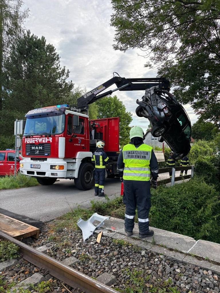 Zug crasht Auto samt "STOP"-Schild in Straßengraben
