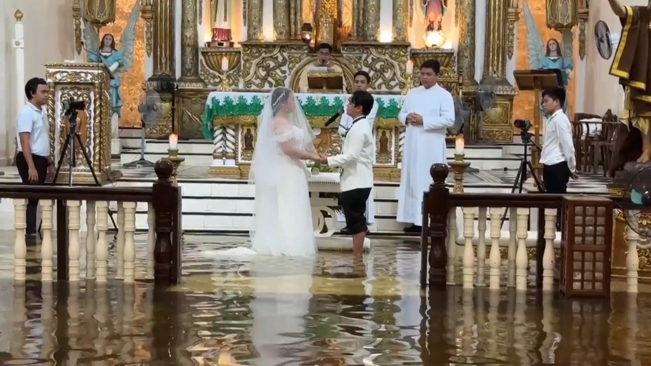 Here comes the tide: couple wades down aisle as flooding hits wedding in central Philippines