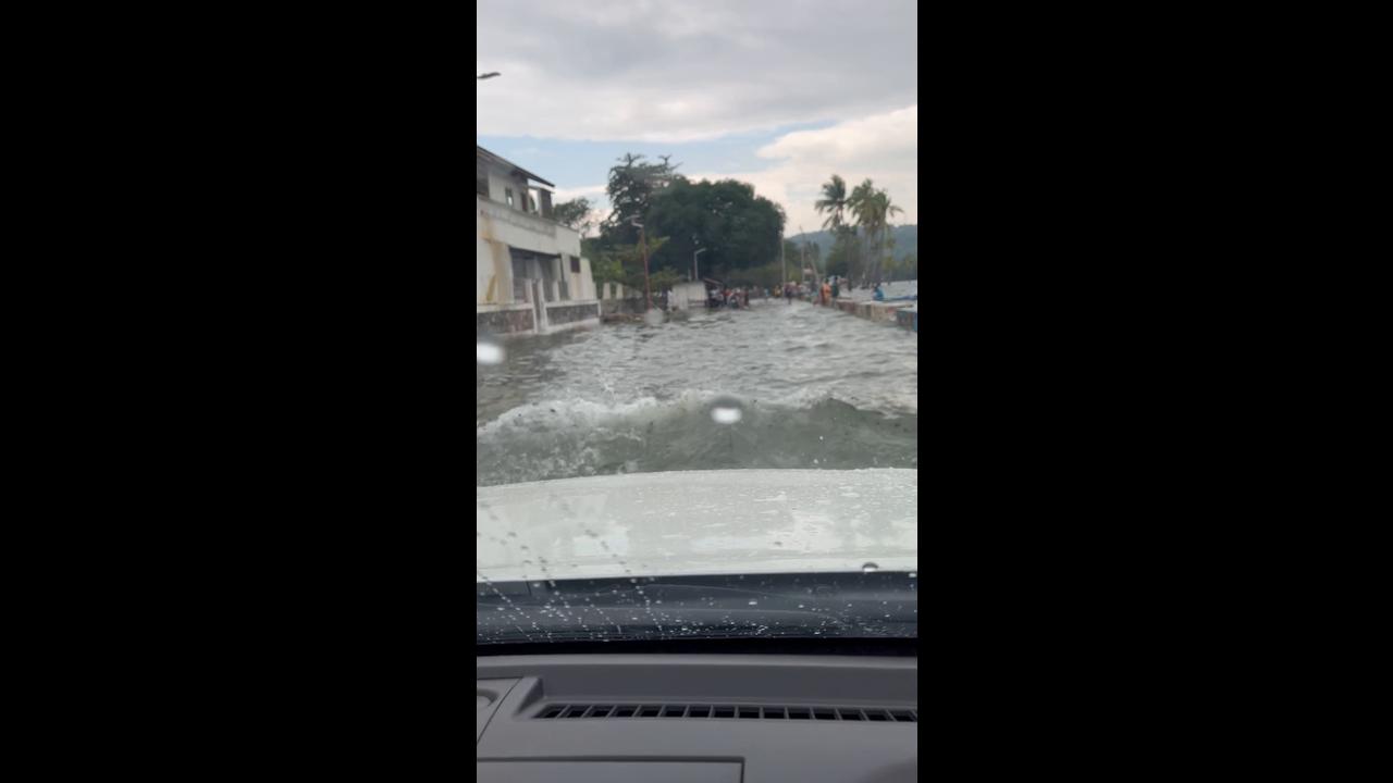Driver maneuvers through flooded road as lake overflows after storm