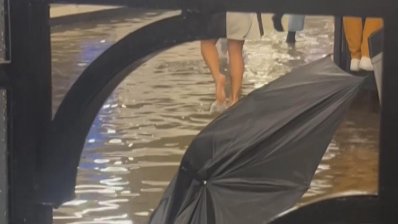Subway passengers walk in flood waters in New York train station