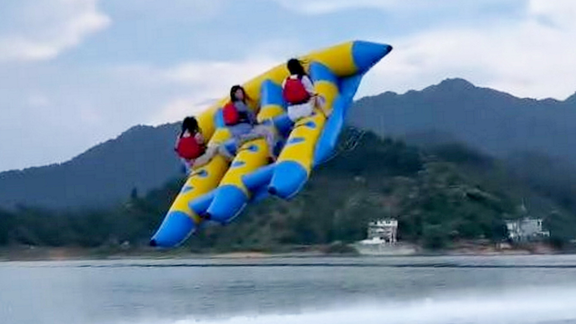 Banana boat goes airborne before flipping and tossing riders into lake