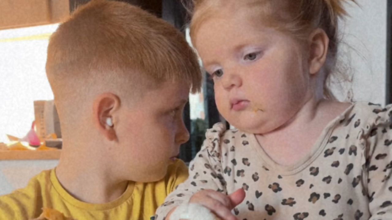 Little girl steals a bite while boy looks away and grins mischievously