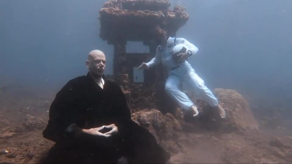 Monk Holds Breath and Poses Next to Underwater Temple