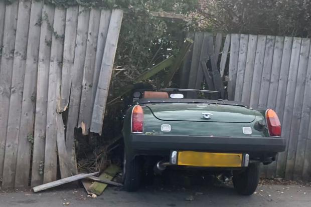 Convertible car crashes head on into fence on a busy road