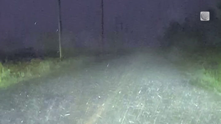 Hail pings off the road as a car drives in Québec thunderstorm