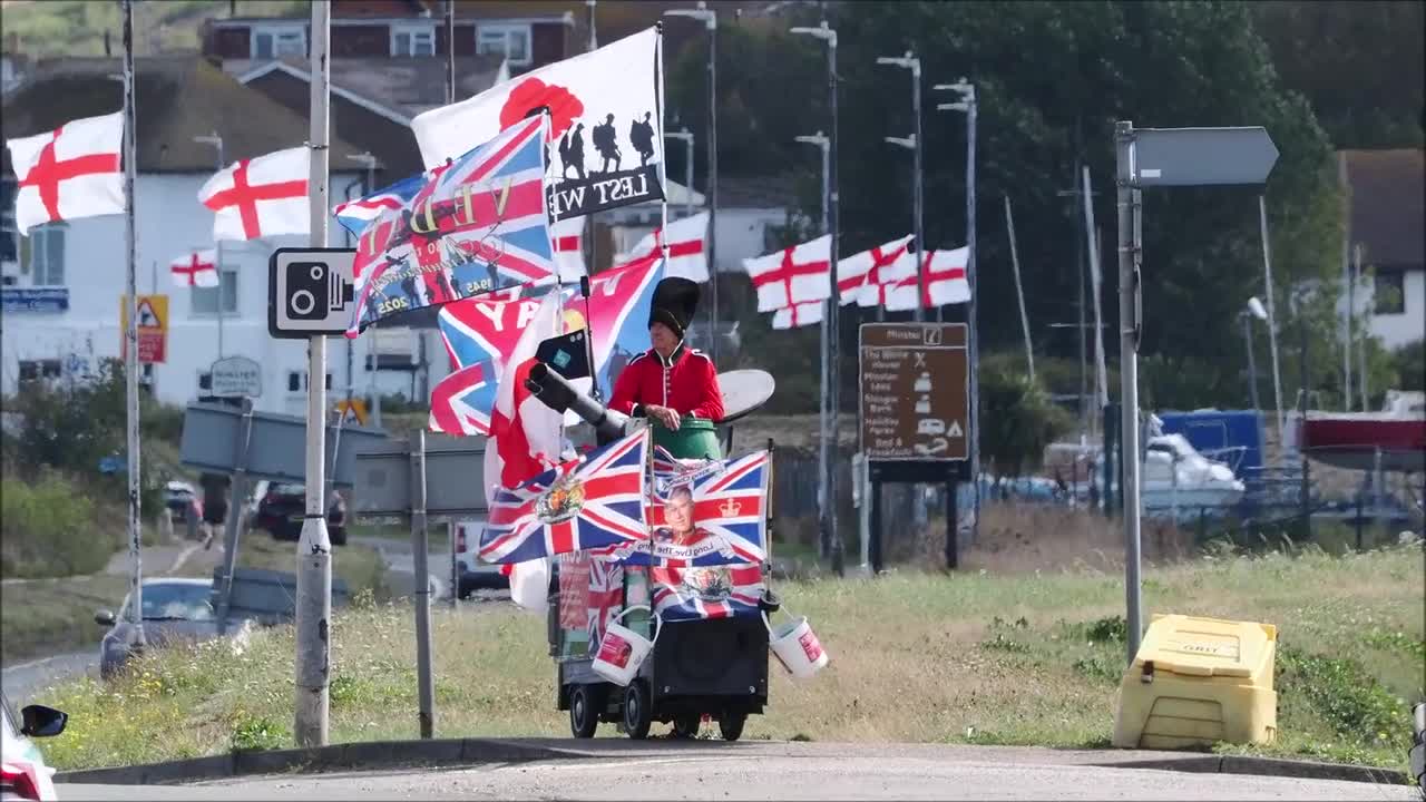 Kent man parades mobility scooter tank along flag-lined street, UK