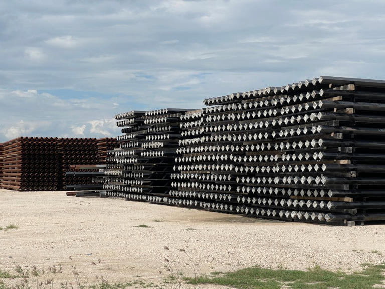 Black border wall bollards stacked up at Rio Grande Valley stockyard