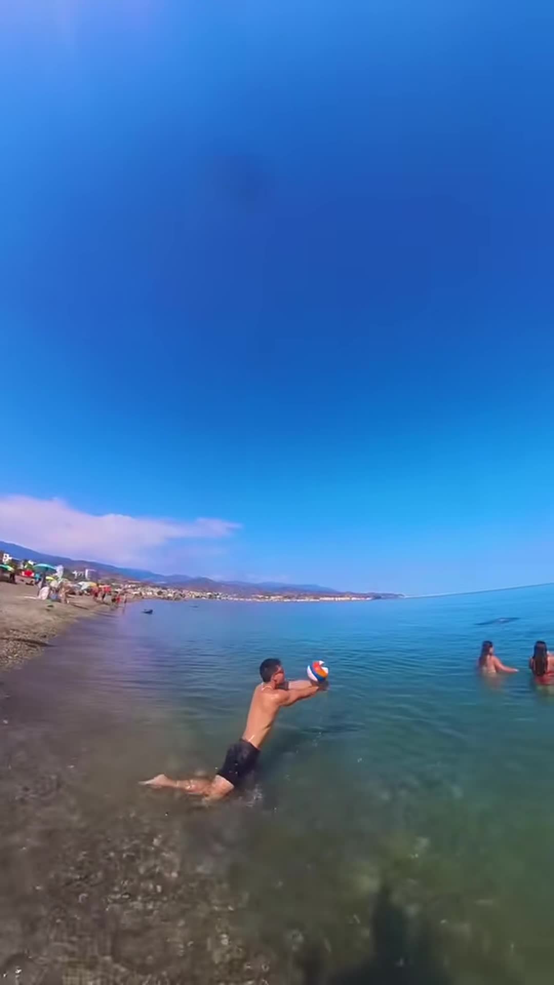 Friends Playing Beach Volleyball along the Seashore under Clear Blue Skies
