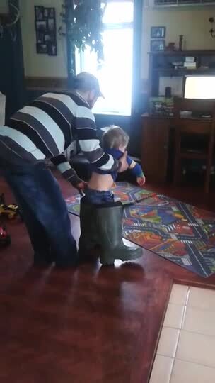 Kid Falls Attempting to Walk in Dad's Boots