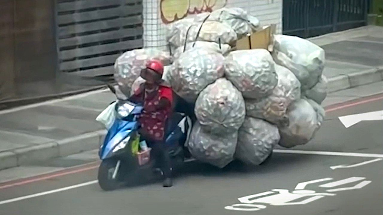 Woman rides scooter overloaded with aluminium cans in Taiwan
