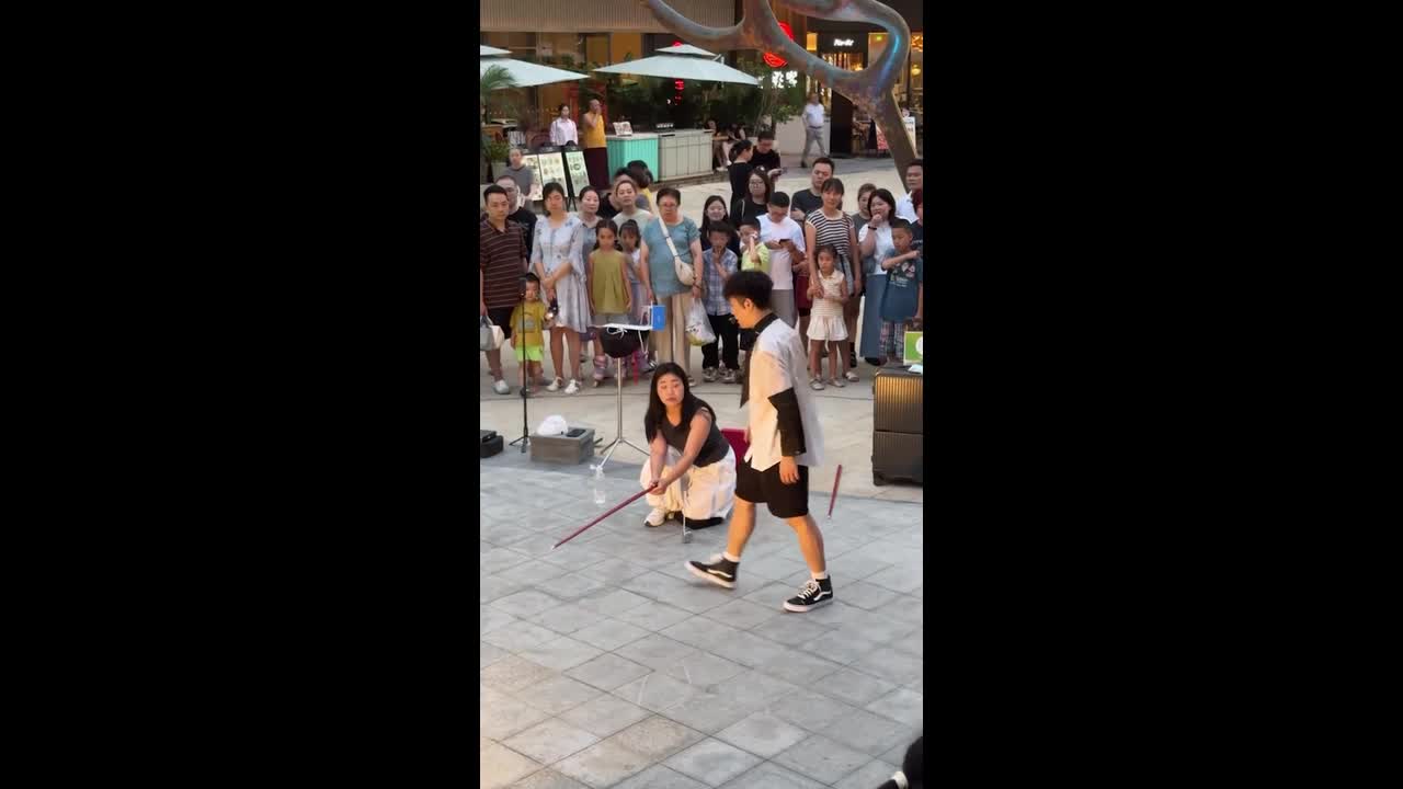 Street performer slides under low pole with acrobatic skill