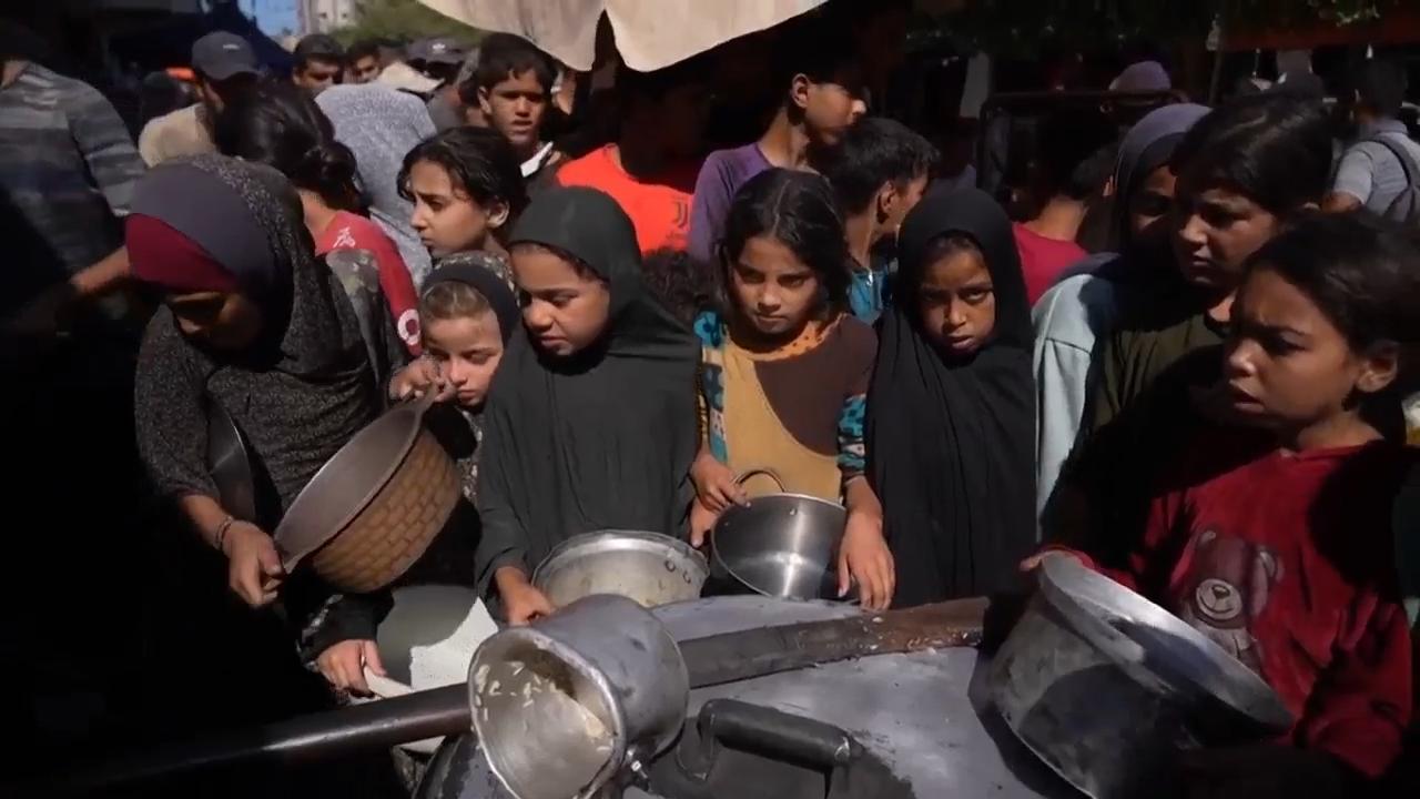 Palestinians wait to receive food at a community kitchen in central Gaza