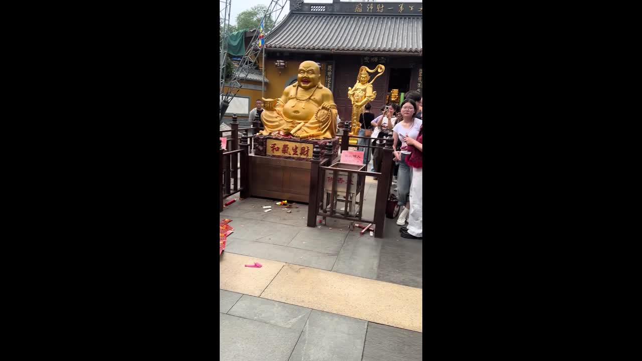 Tourist does his scratch cards in front of Buddha statue for good luck