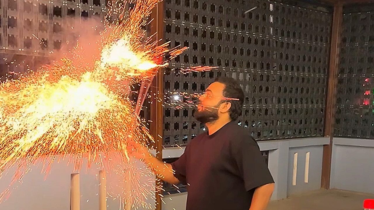 Man holds lit firework rocket in hand to predictable results