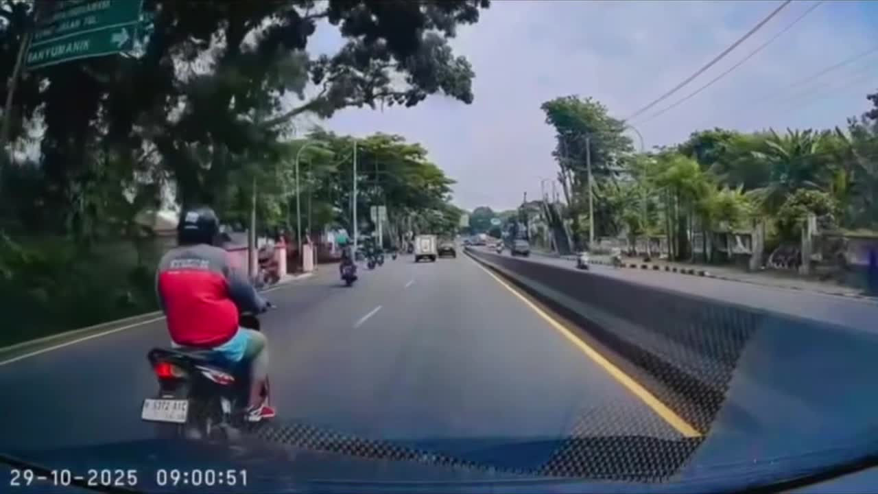 Motorcyclist knocked over by a truck scrambles to avoid wheels