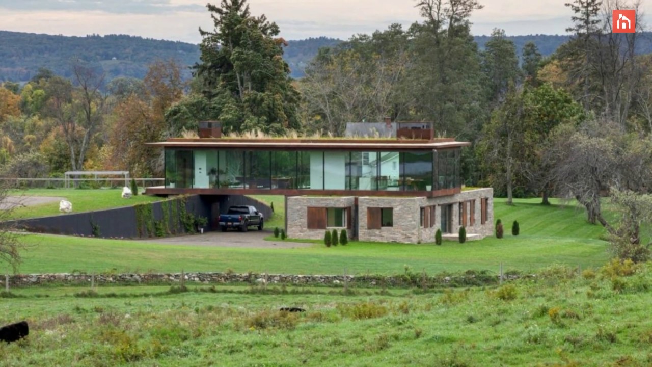 A stone and glass country house half-hidden behind a slope