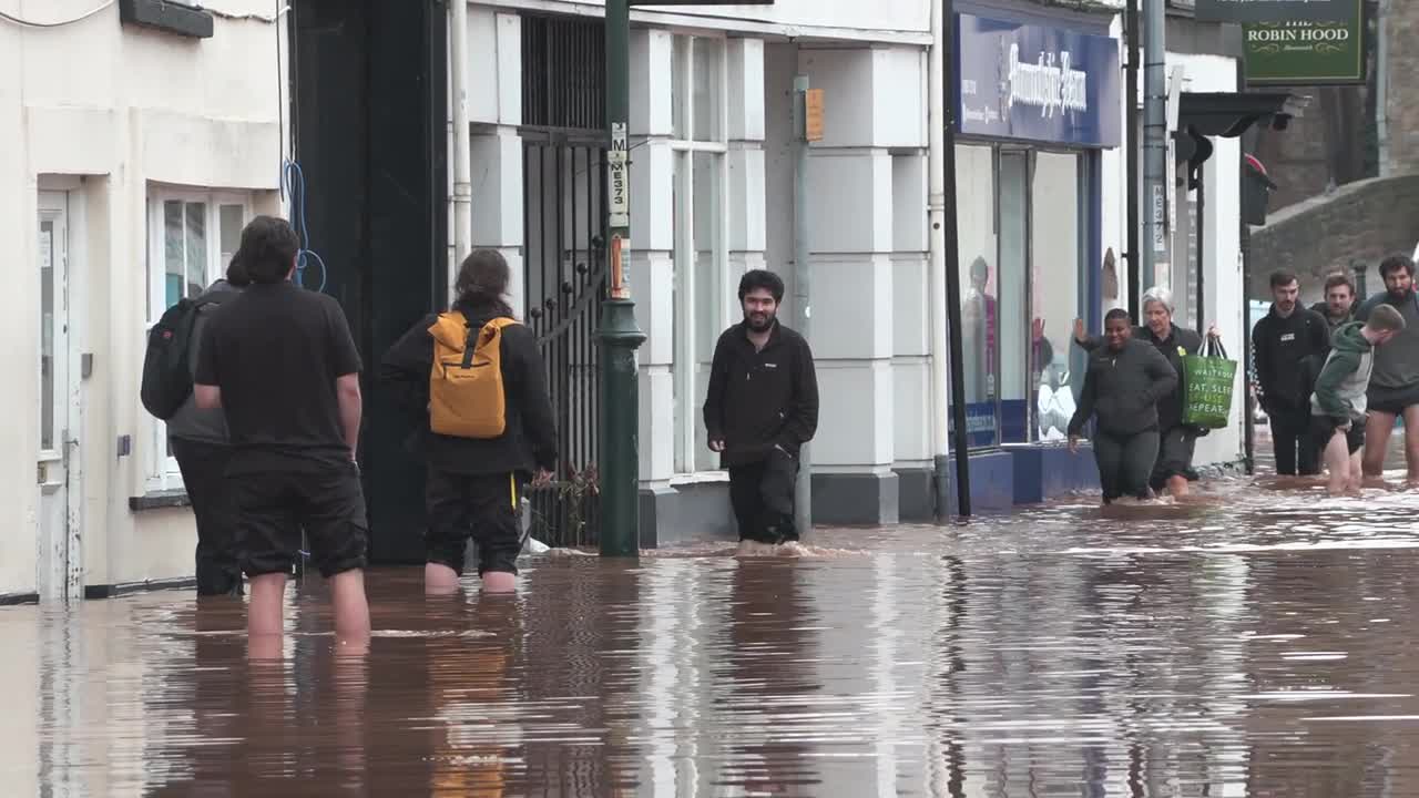 Supermarket workers wade through floodwater after being trapped in ...