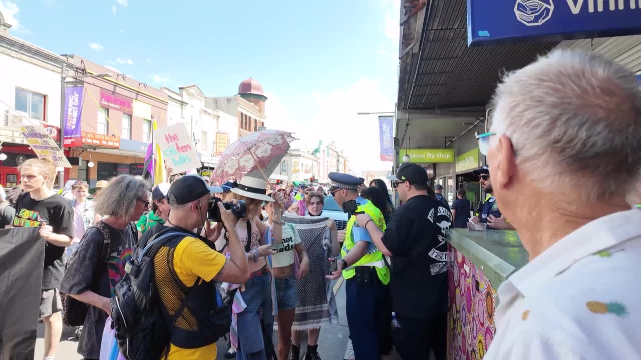 Police speak to a man filming the Trans Day of Resistance Rally 2025