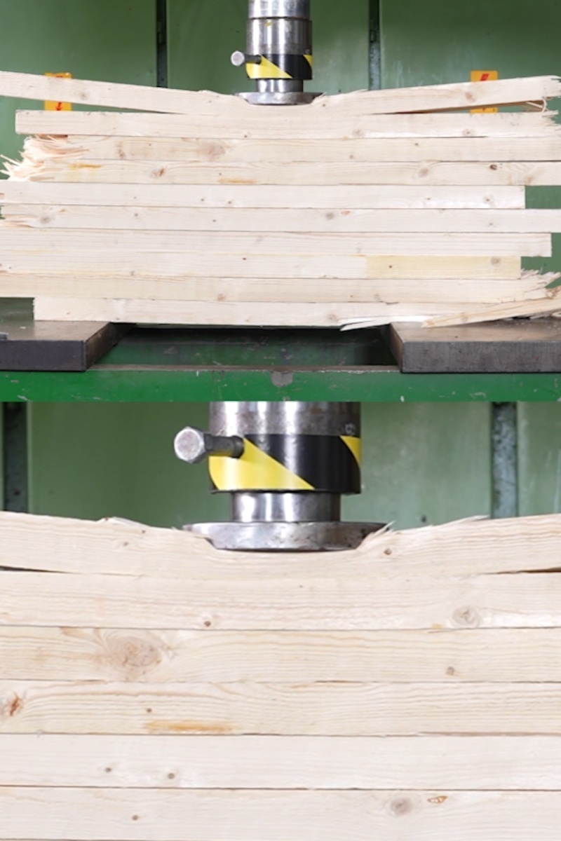 Hydraulic press crushing stack of wooden planks