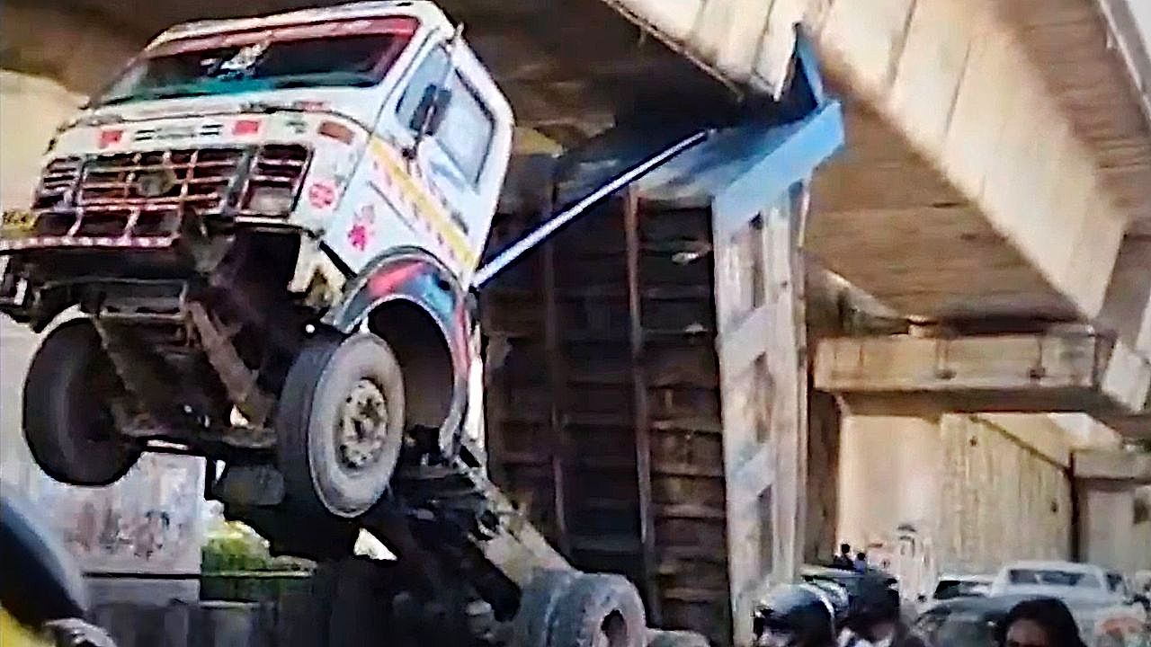 An overloaded garbage truck overturned and was left hanging from an ...