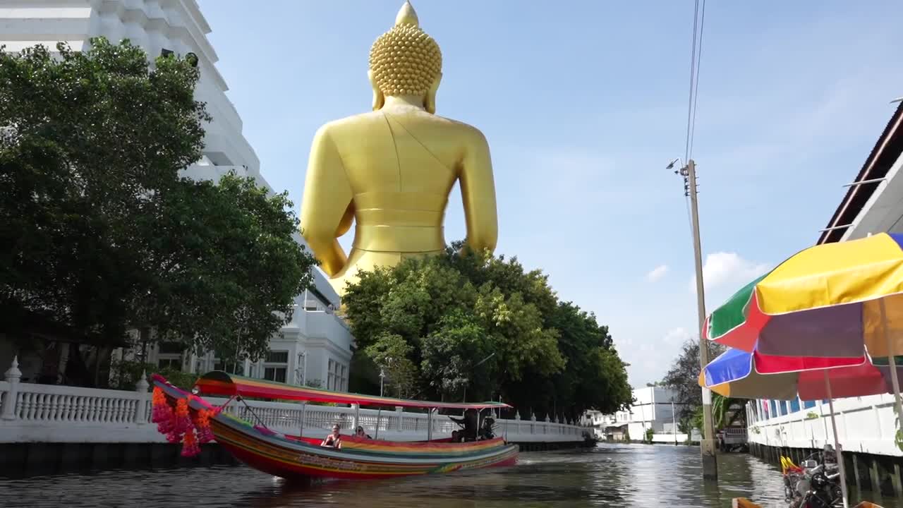Tourists feed fish in front of giant Buddha statue in Bangkok