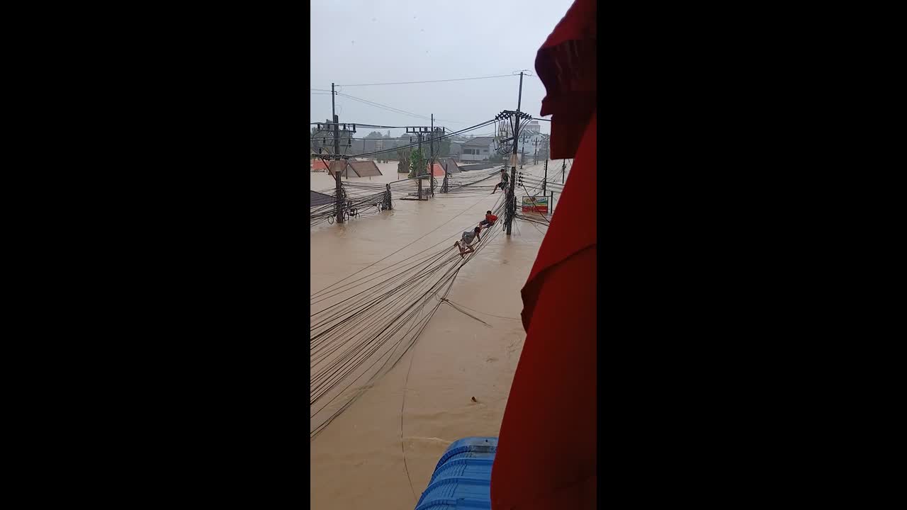 Locals clamber across power lines to escape 8ft deep flood in Thailand