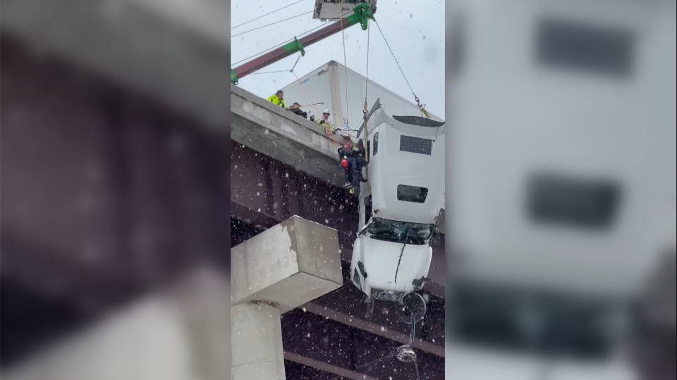 Driver rescued from tractor-trailer dangling over bridge