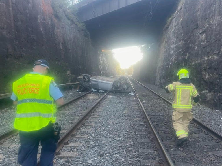Chaos after car crashes onto train tracks