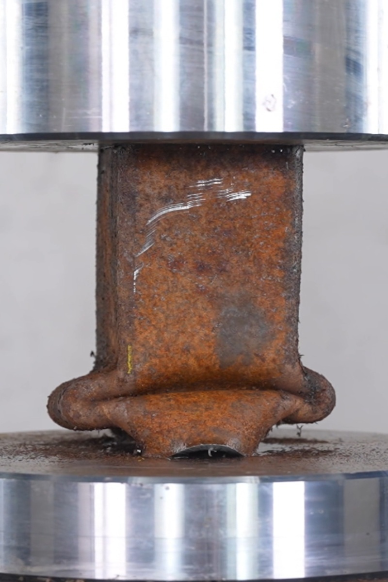 Rusted metal object under hydraulic press