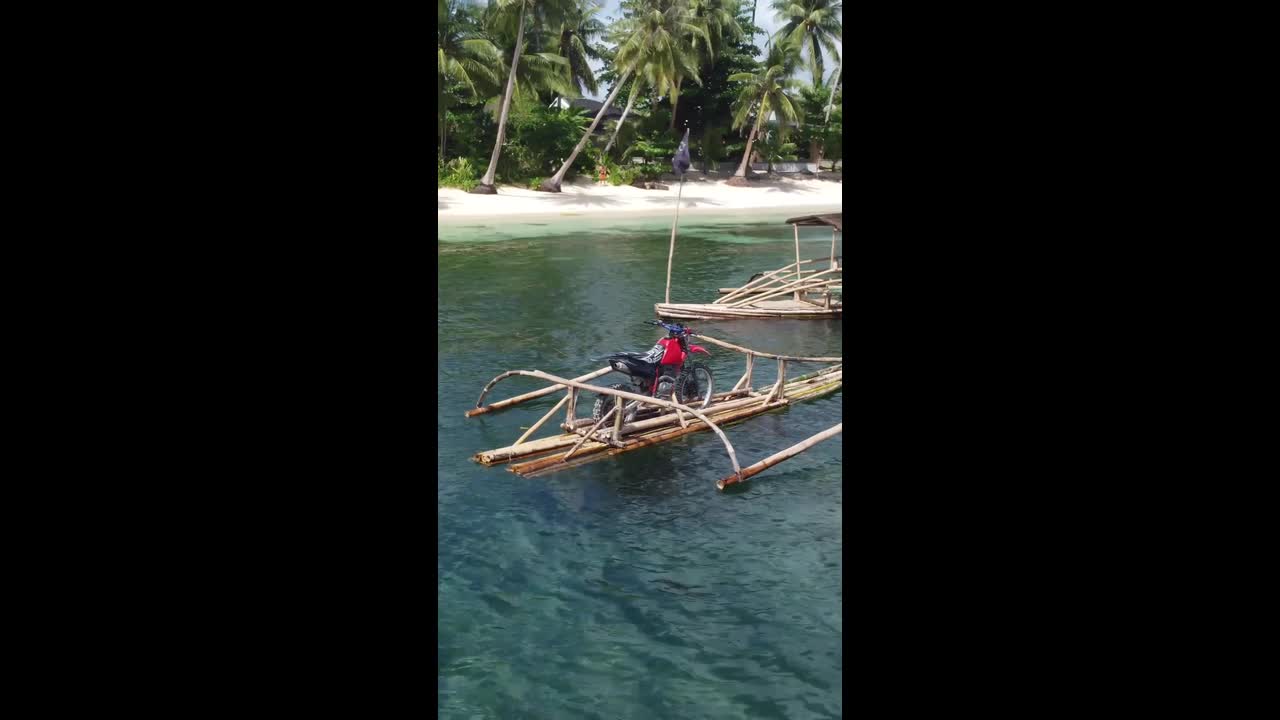 Locals use bamboo raft to carry tourist's scooter across sea