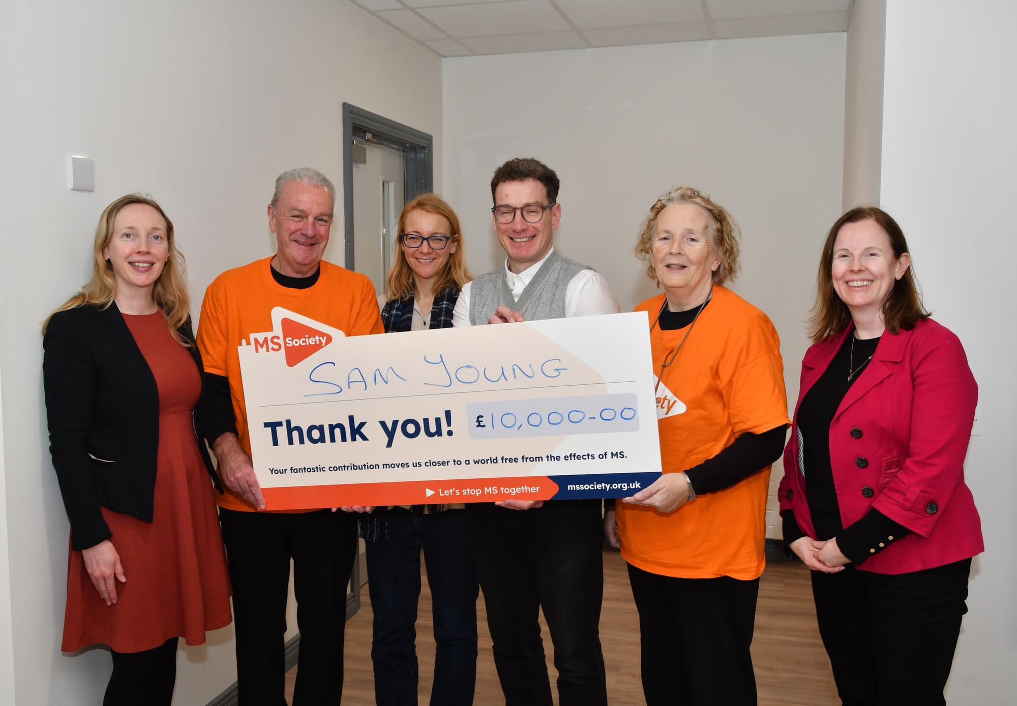 Carrickfergus author Sam Young presents £10,000 to MS Research Hub at QUB