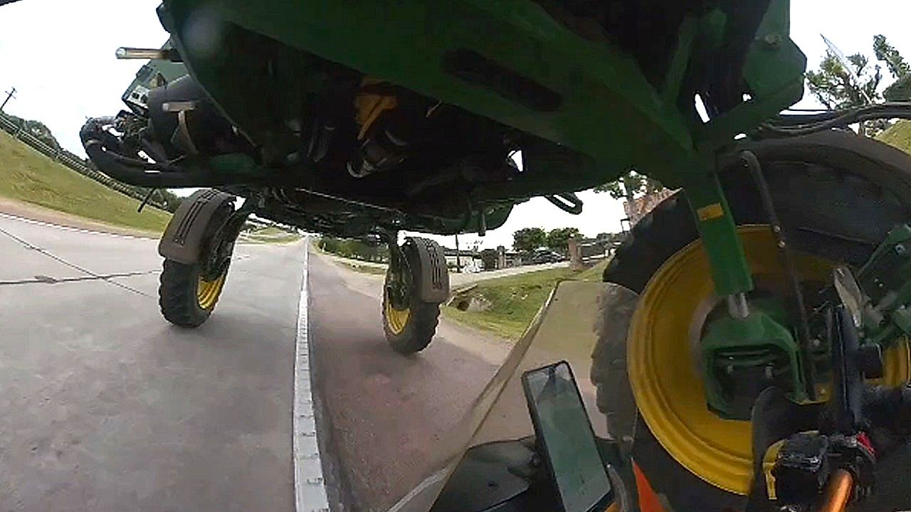Motorcyclist pulls off risky ride under moving tractor