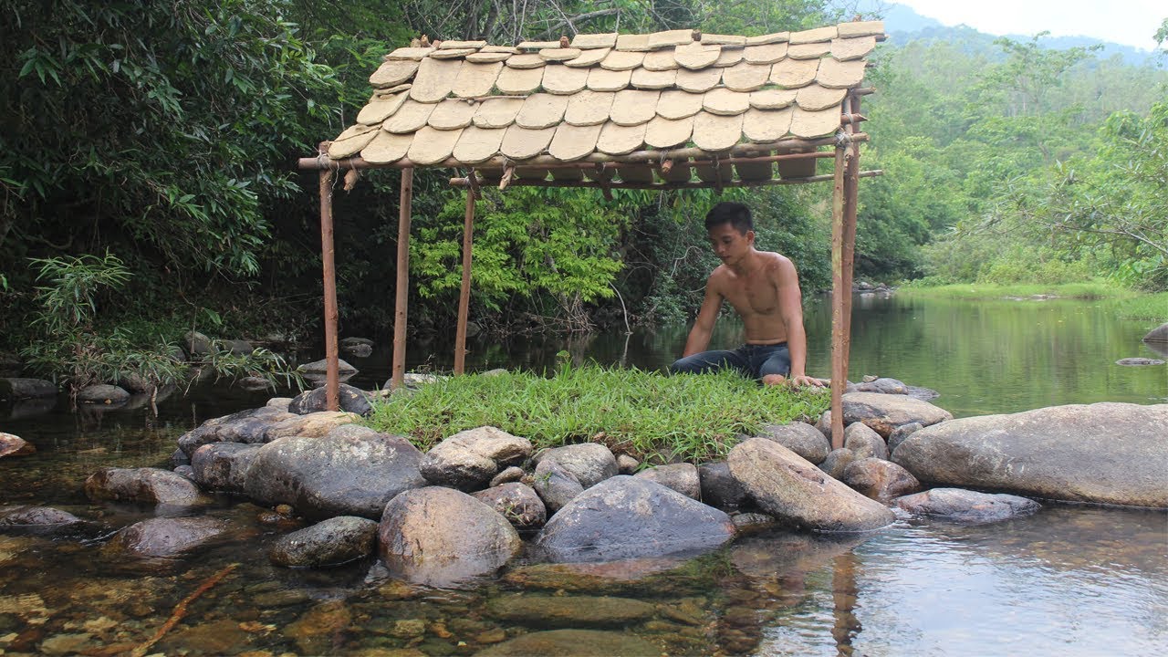 Technologie primitive : construire une hutte au toit de tuiles au bord ...